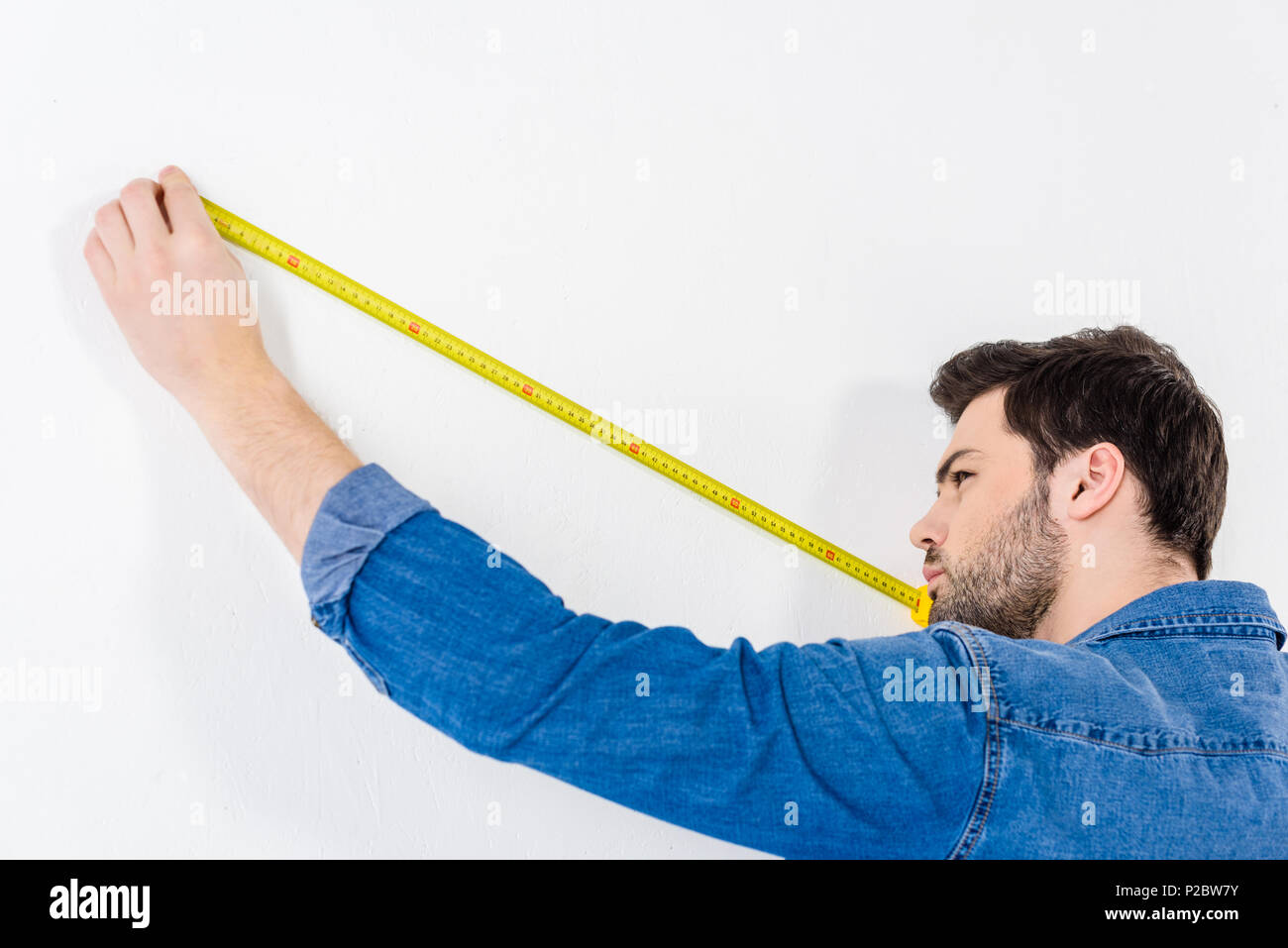 man measuring wall with tape measure on white Stock Photo - Alamy