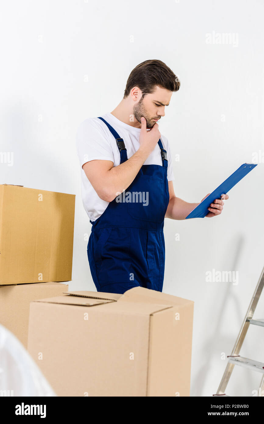 thoughtful relocation service worker looking at clipboard Stock Photo ...