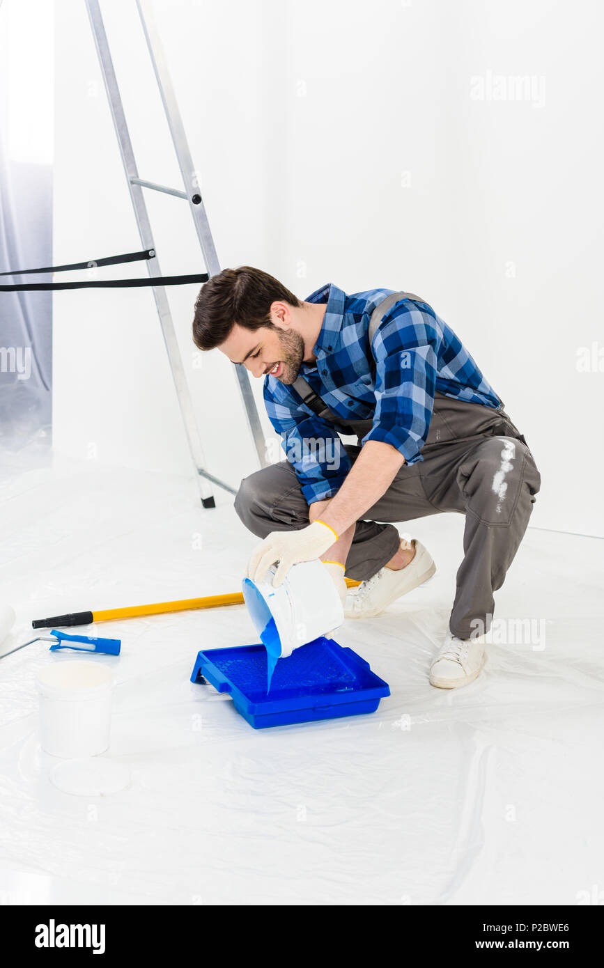 smiling man pouring paint from bucket into plastic paint tray Stock ...