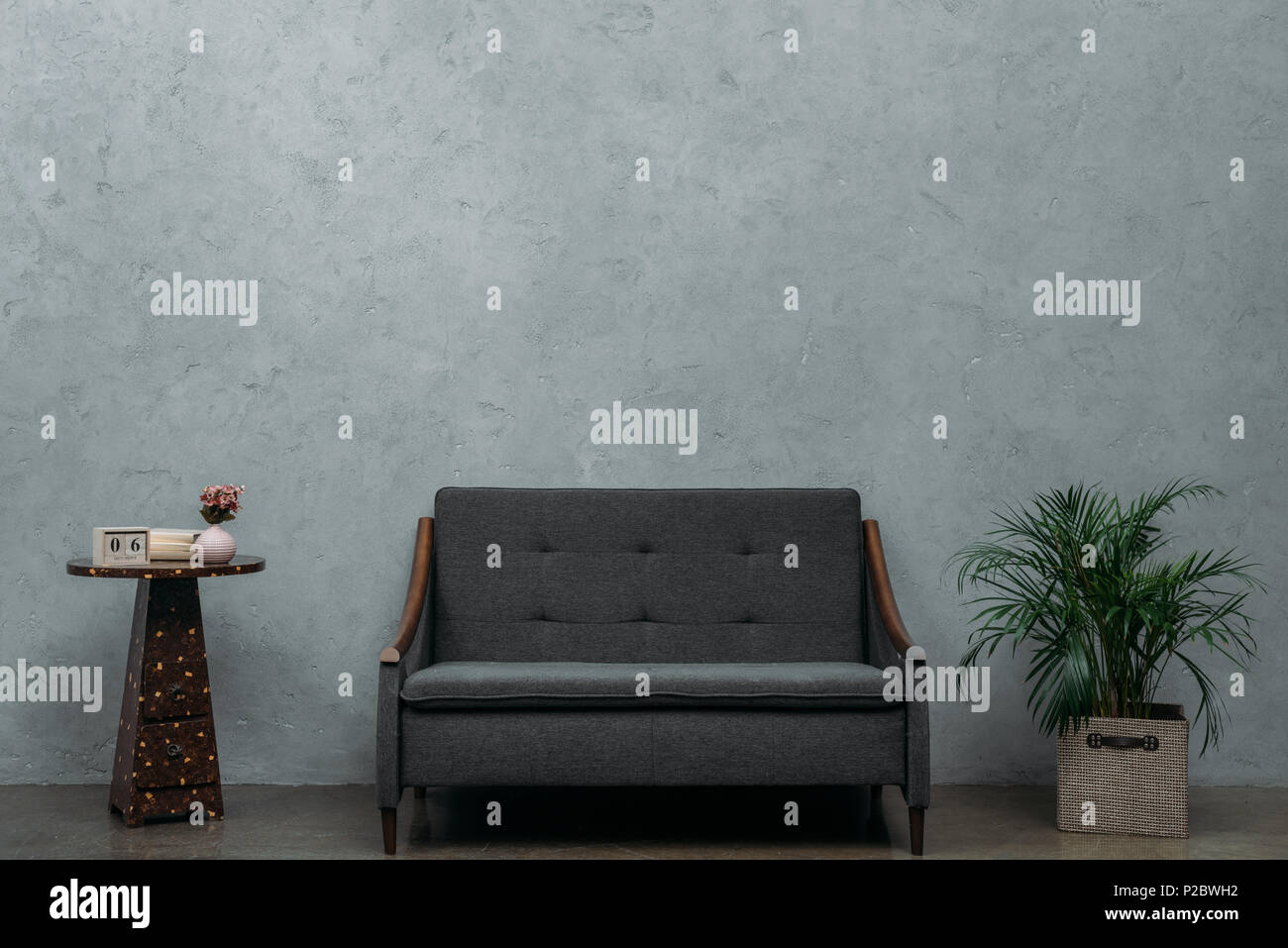cozy empty sofa and calendar on table and green houseplant near grey ...