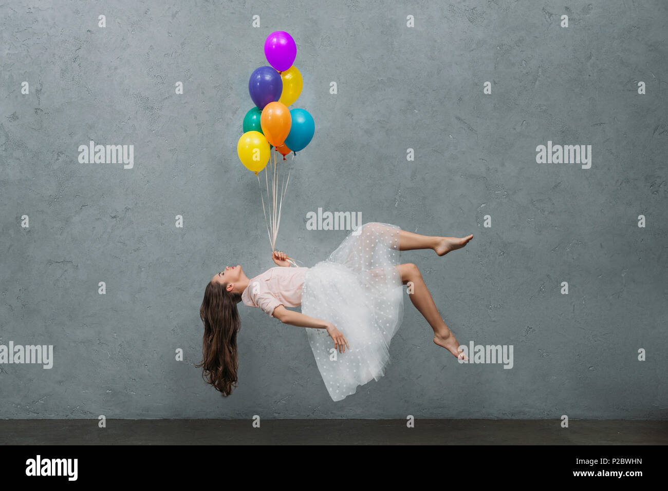young woman levitating with colorful balloons Stock Photo - Alamy