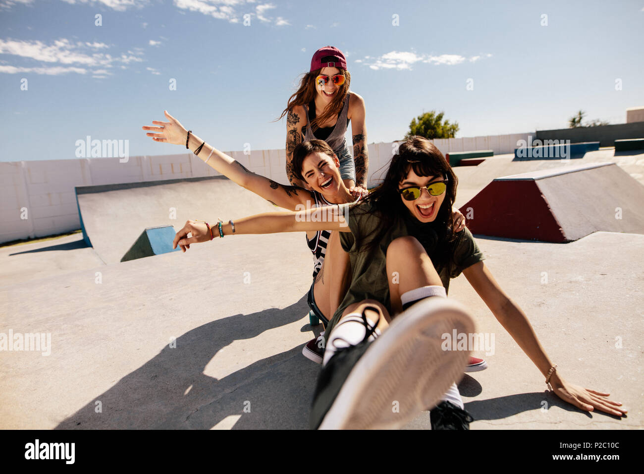 Three female friends playing with skateboard at the skate park. One ...