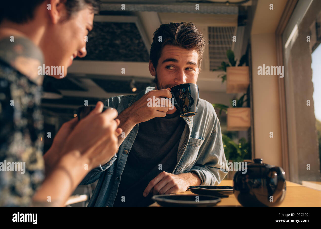 Young man drinking coffee with his girlfriend at coffee shop. Couple ...