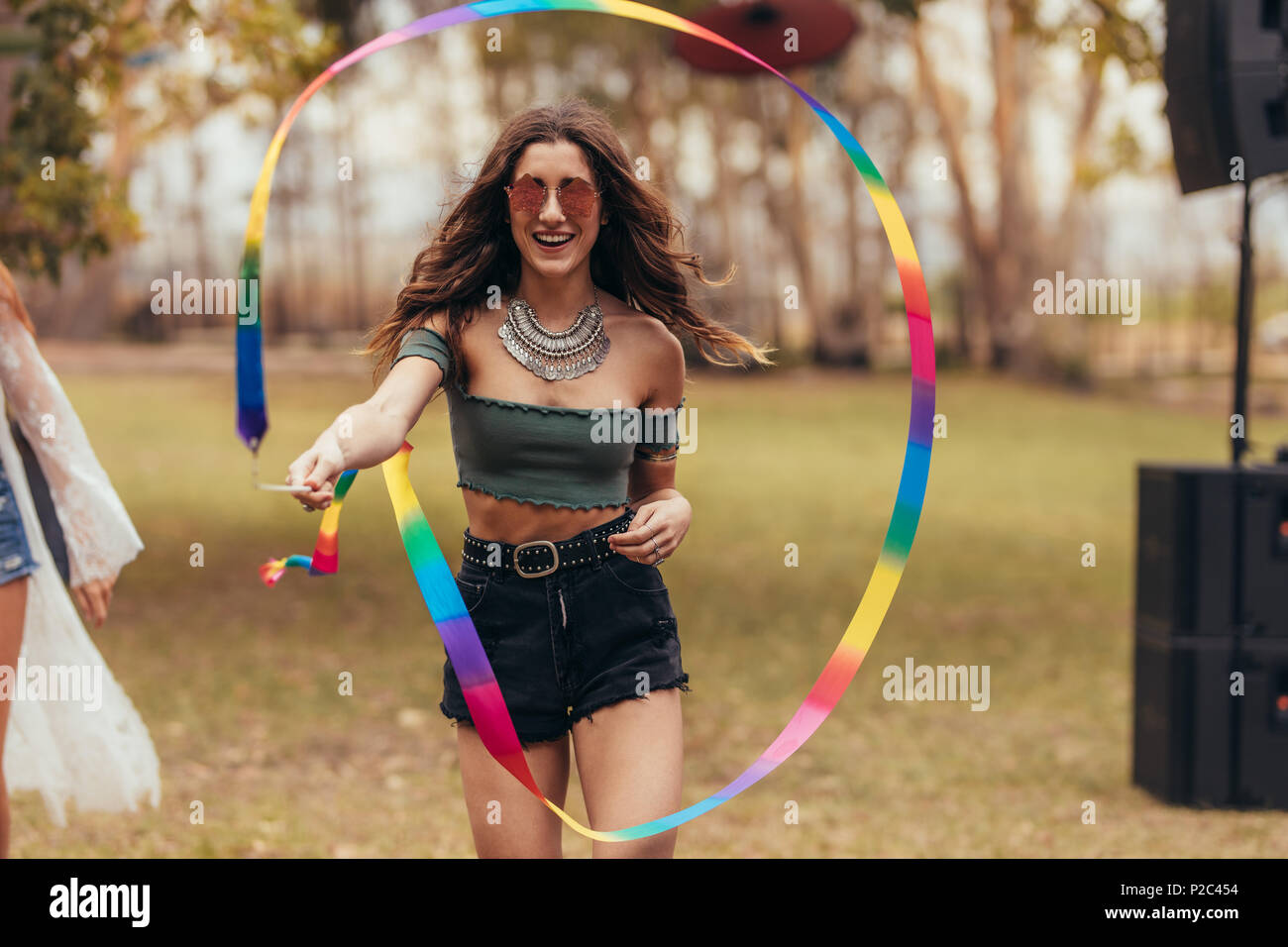 Beautiful young woman playing with ribbon stick at music festival ...
