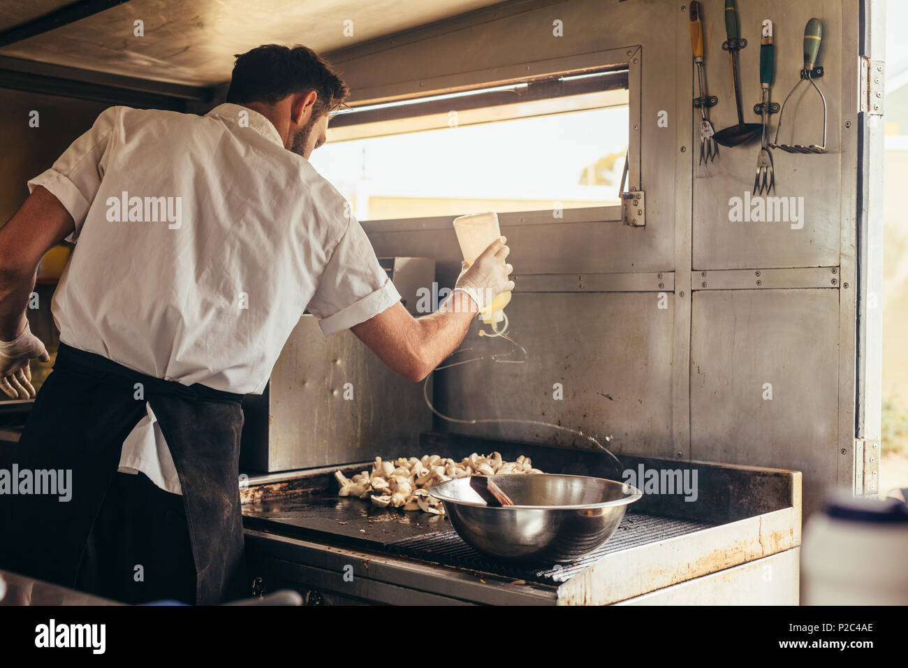 Young chef cooking some of his favorite dishes in a food truck. Man ...