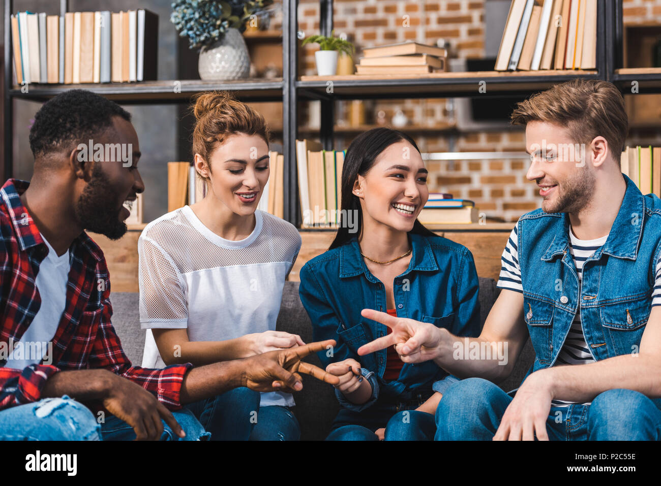 happy young multiethnic friends playing game of rock, paper, scissors ...