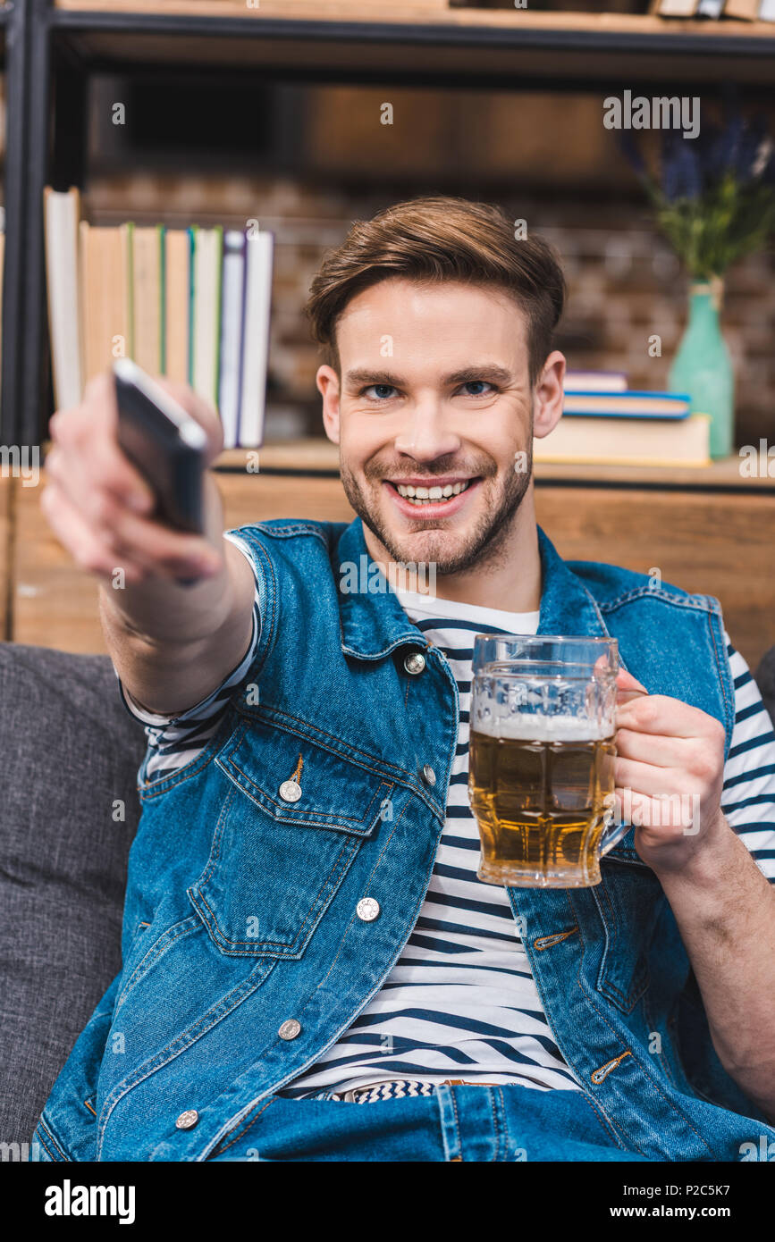 smiling young man holding glass of beer and remote controller Stock ...