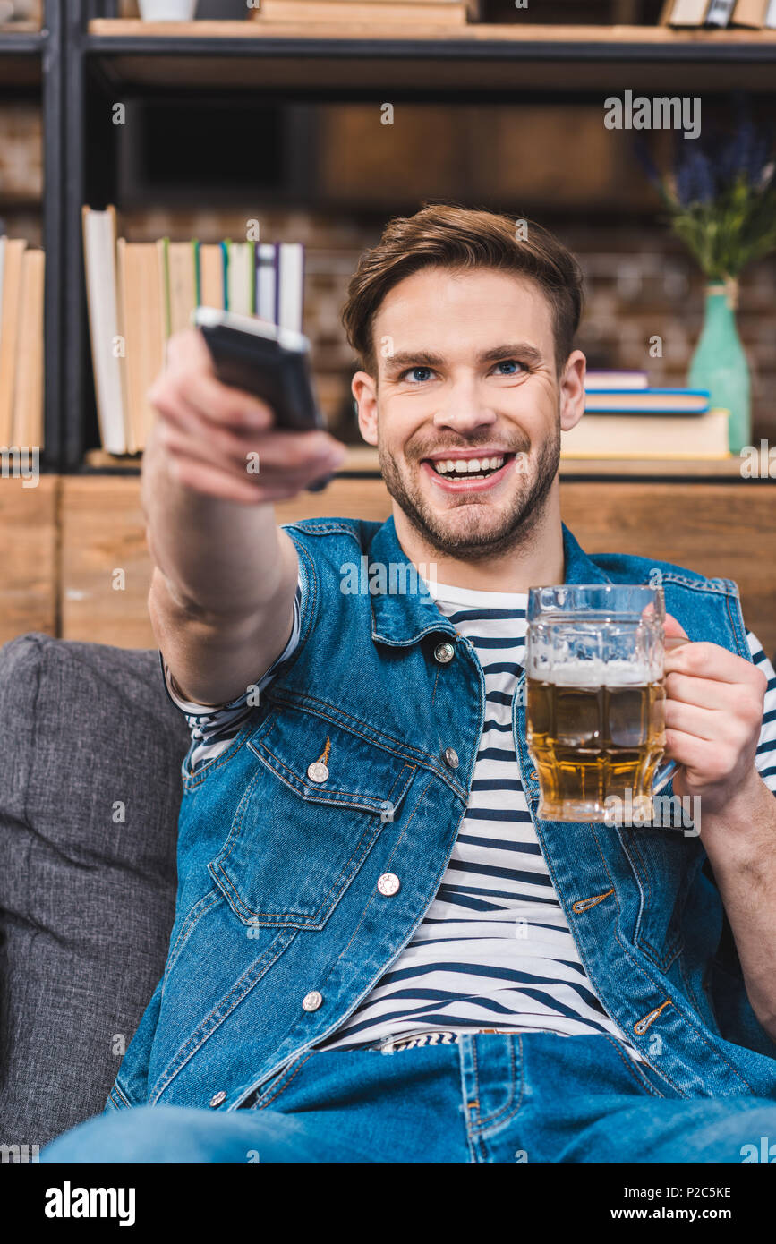 happy young man holding glass of beer and remote controller Stock Photo ...