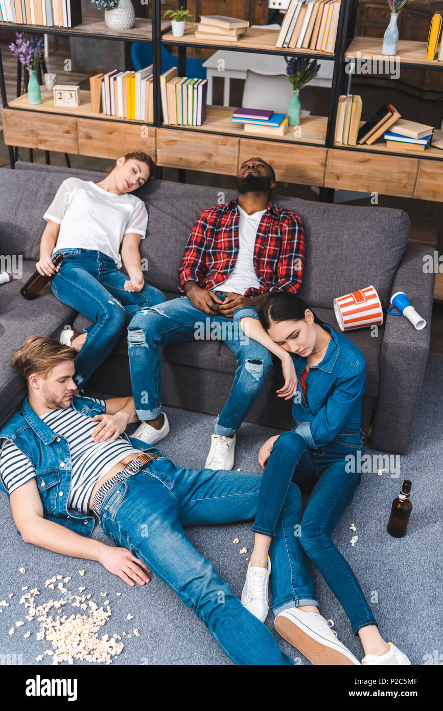high angle view of young multiethnic friends sleeping in messy room ...