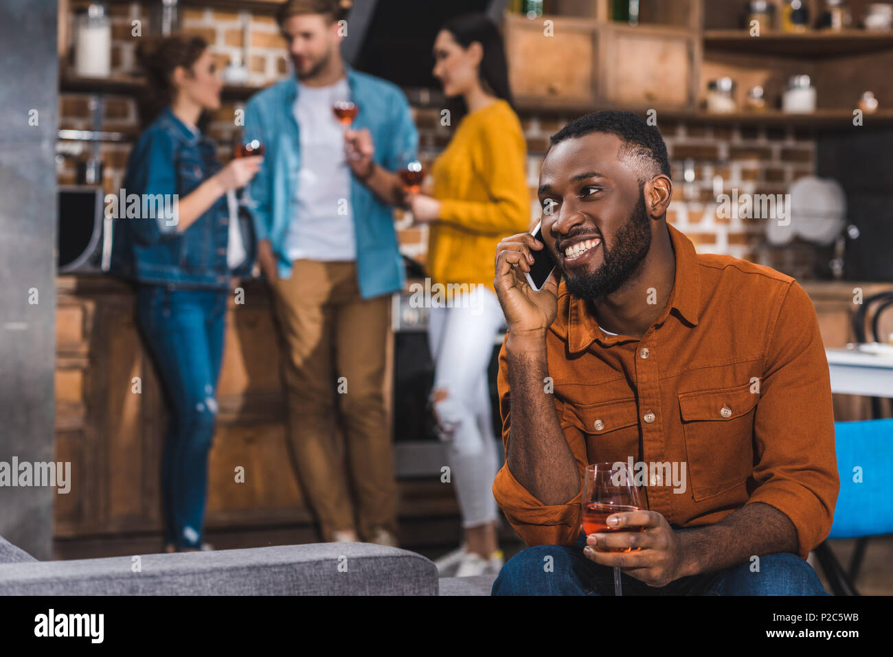 smiling african american man talking by smartphone while friends ...