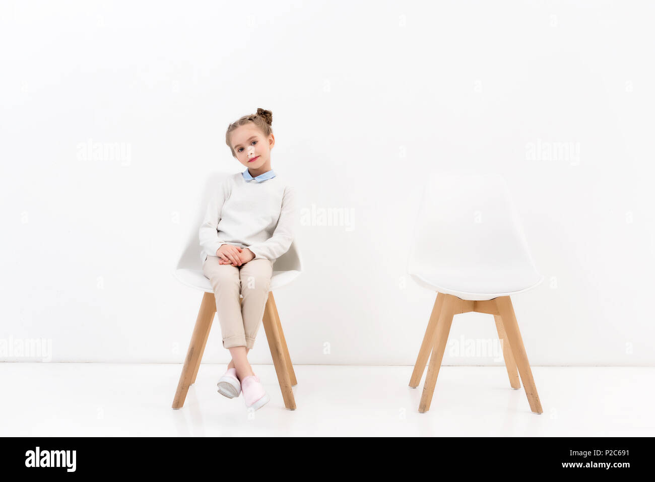 adorable child sitting on chair and looking at camera on white Stock ...