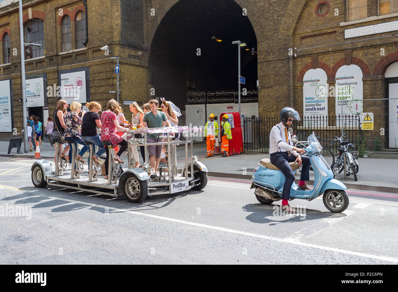 Hen party on a Pedibus following a smartly dressed man on a scooter in ...