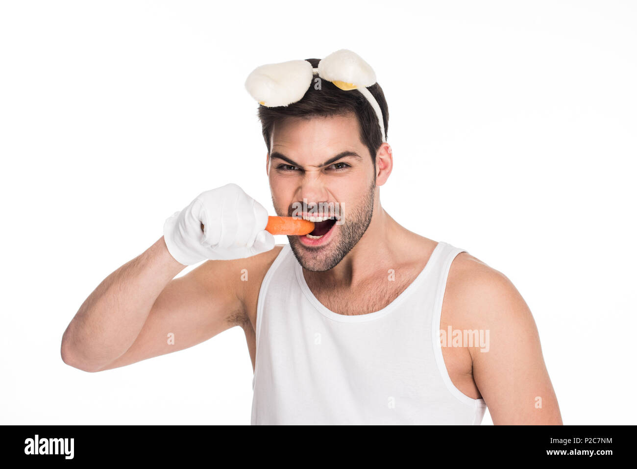 Man with bunny ears biting carrot isolated on white, easter concept ...