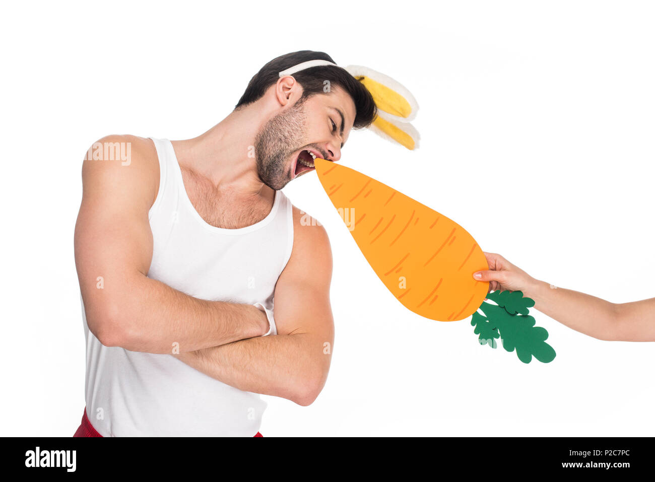 Man with bunny ears biting carrot from female hand isolated on white ...