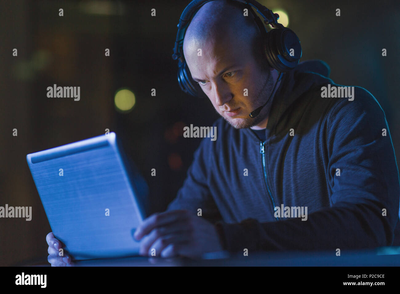 hacker in headset typing on laptop in dark room Stock Photo - Alamy