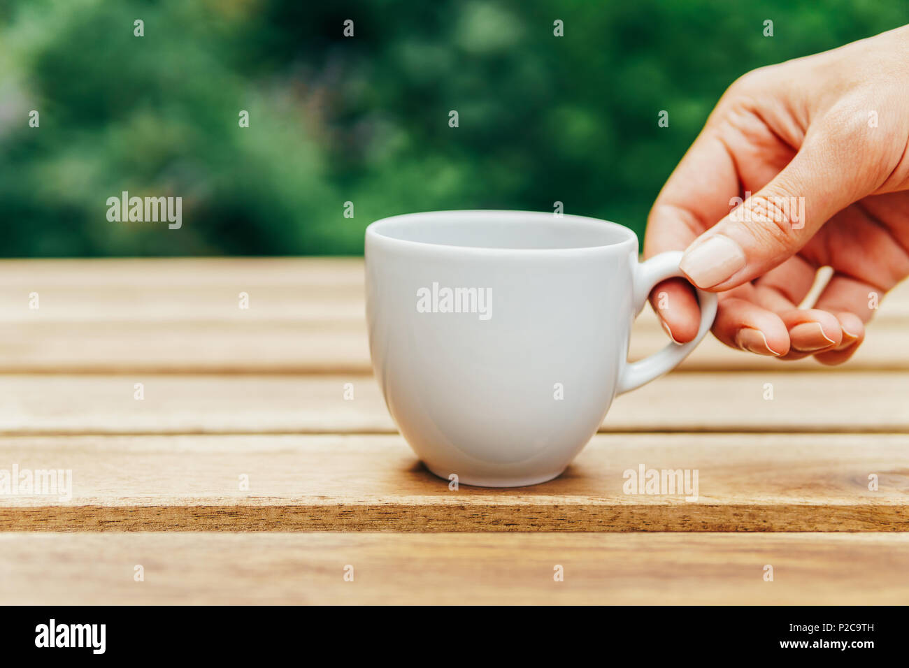 Woman Hand Raising A Cup Of Coffee From Wooden Table In Garden Stock ...