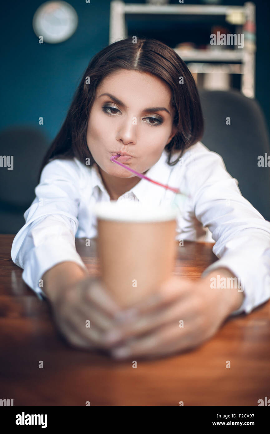 Tired lady drinking from straw Stock Photo - Alamy