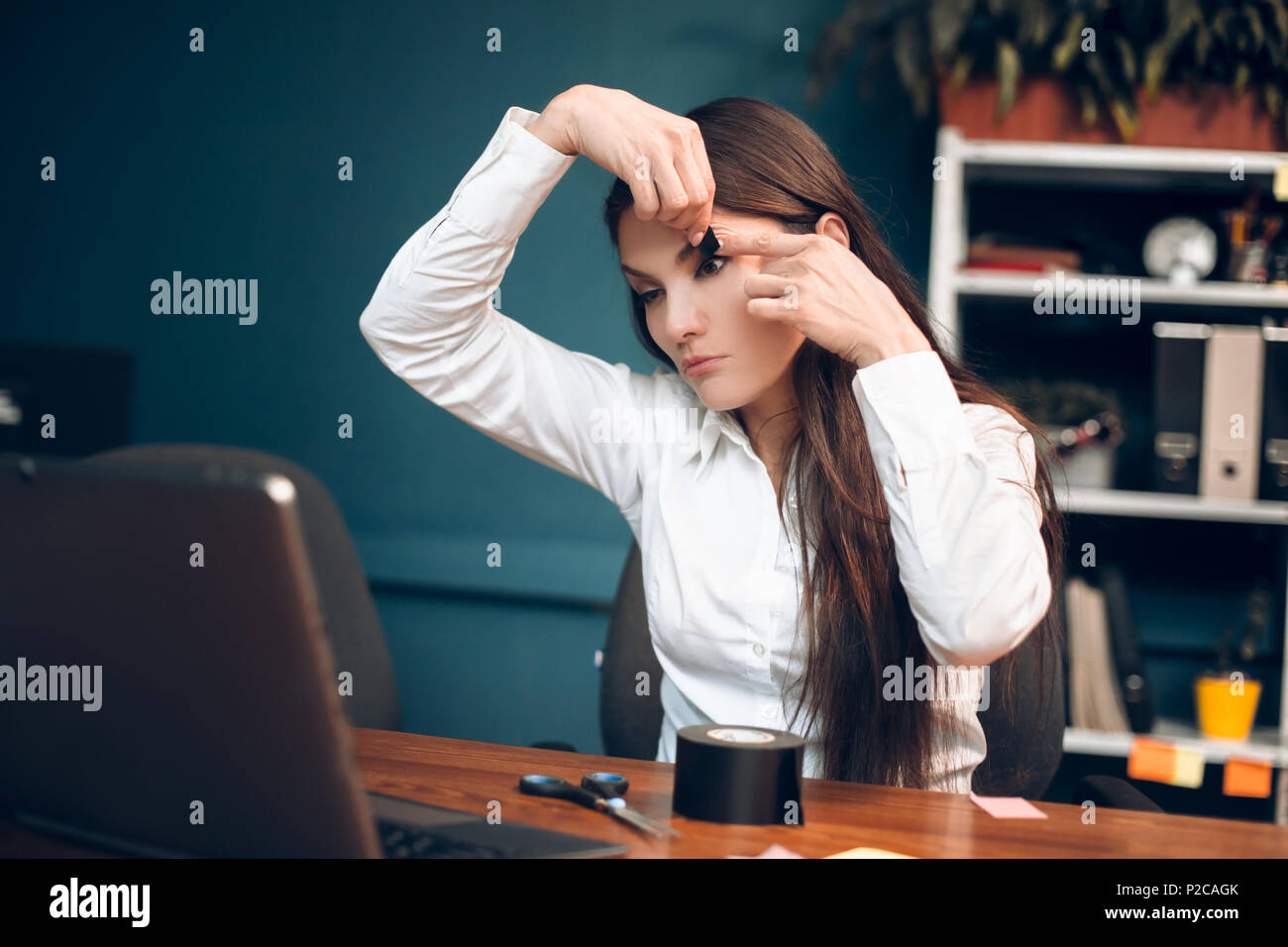 Woman trying to keep her eyes open while working Stock Photo - Alamy
