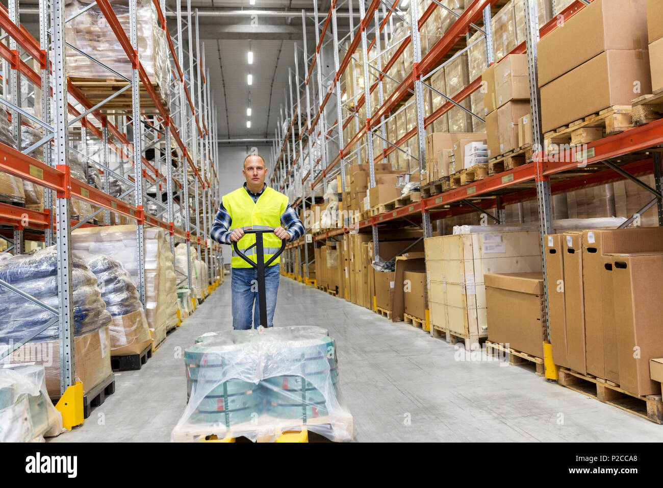 warehouse worker carrying loader with goods Stock Photo - Alamy
