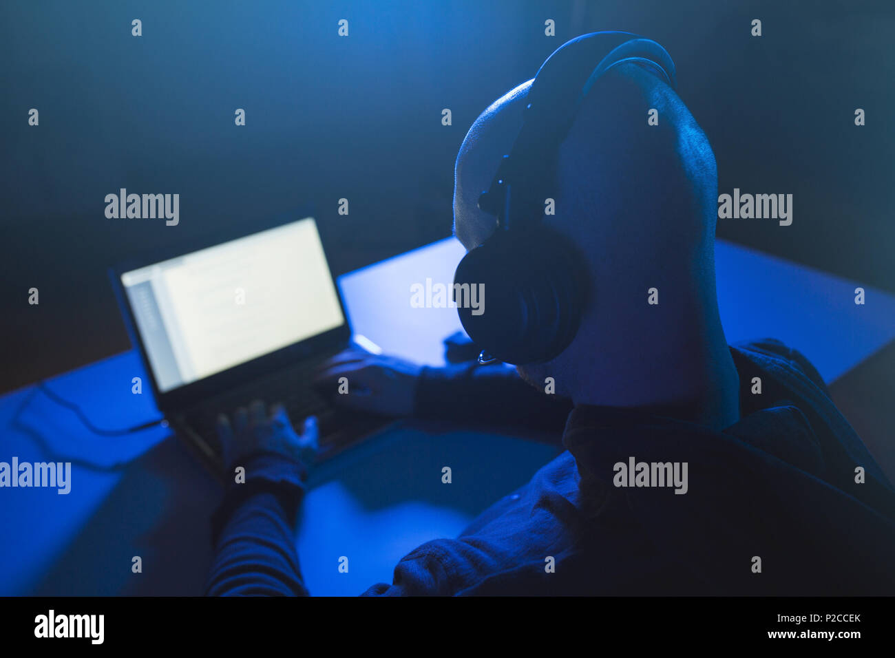 hacker with headset typing on laptop in dark room Stock Photo - Alamy