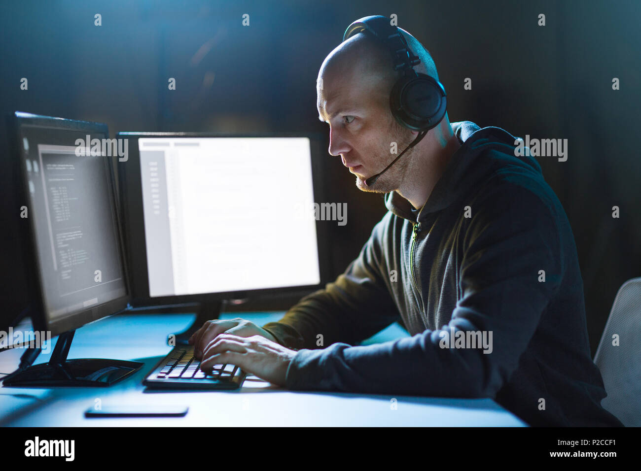 hacker with computer and headset in dark room Stock Photo - Alamy