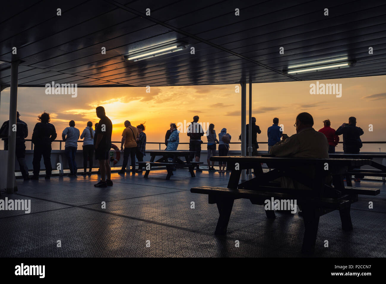 People admiring spectacular sunset from the deck of crossing Ferry ...