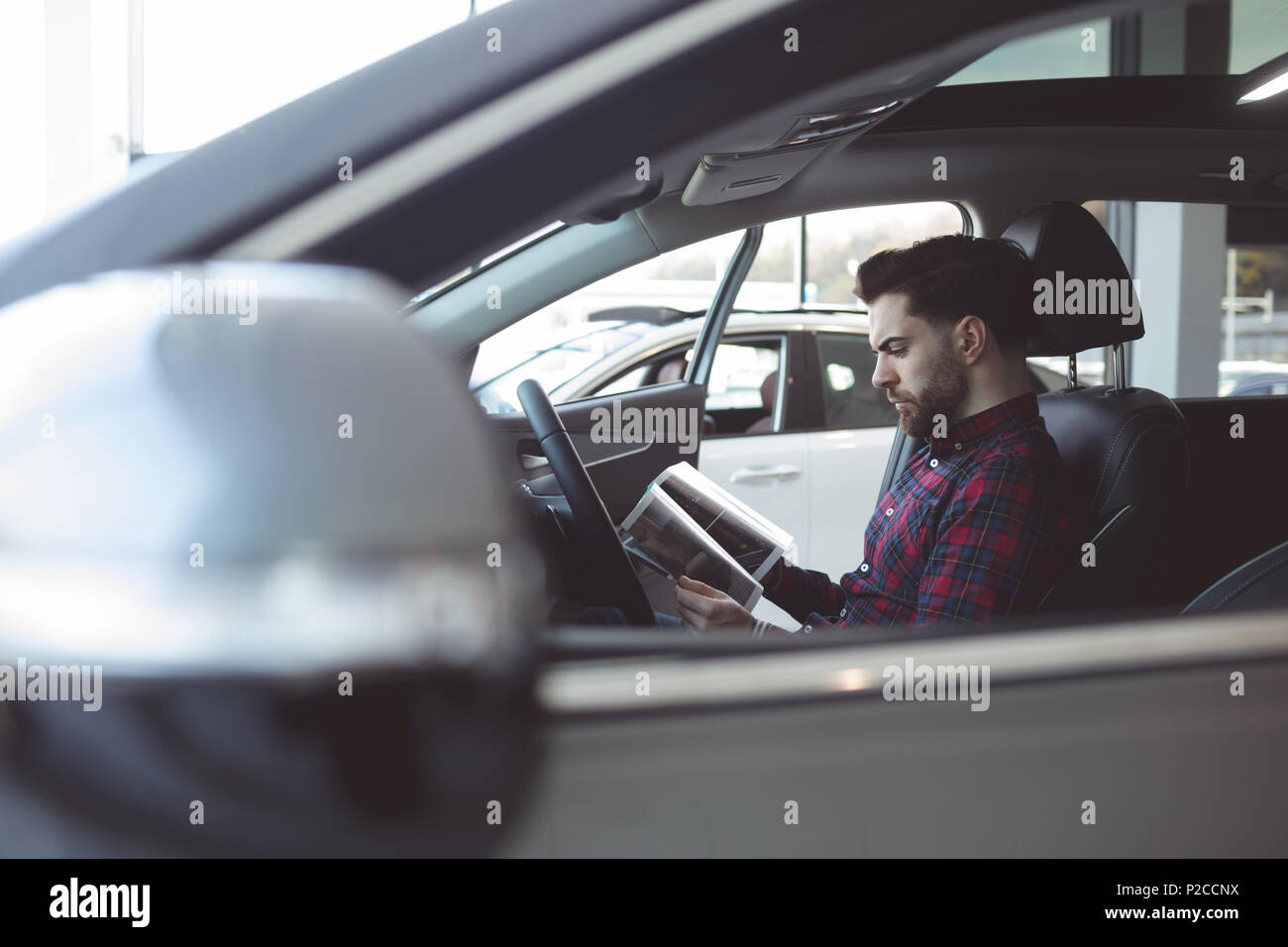 Salesman reading brochure inside the car Stock Photo - Alamy
