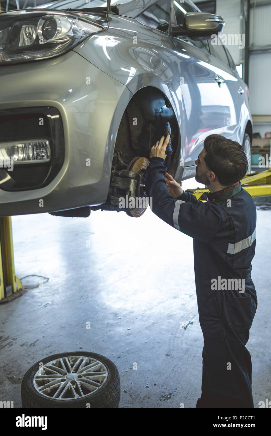 Male mechanic examining a car with torch Stock Photo - Alamy