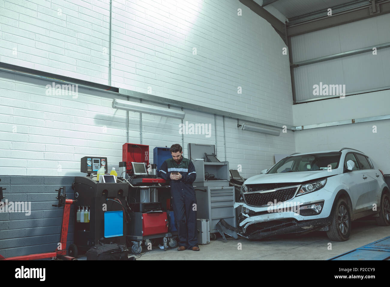 Mechanic using mobile phone while repairing car Stock Photo - Alamy