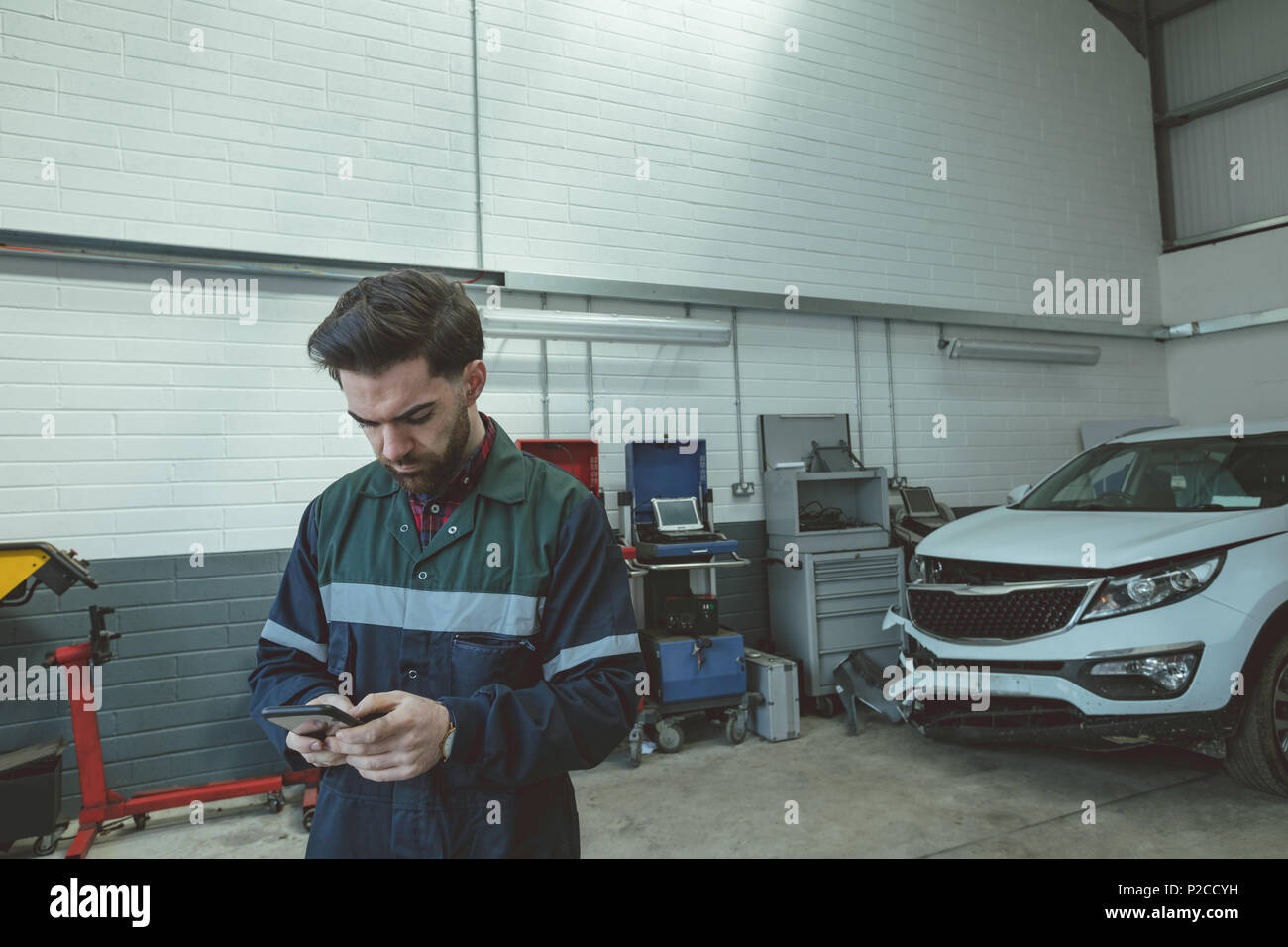 Mechanic using mobile phone while repairing car Stock Photo - Alamy