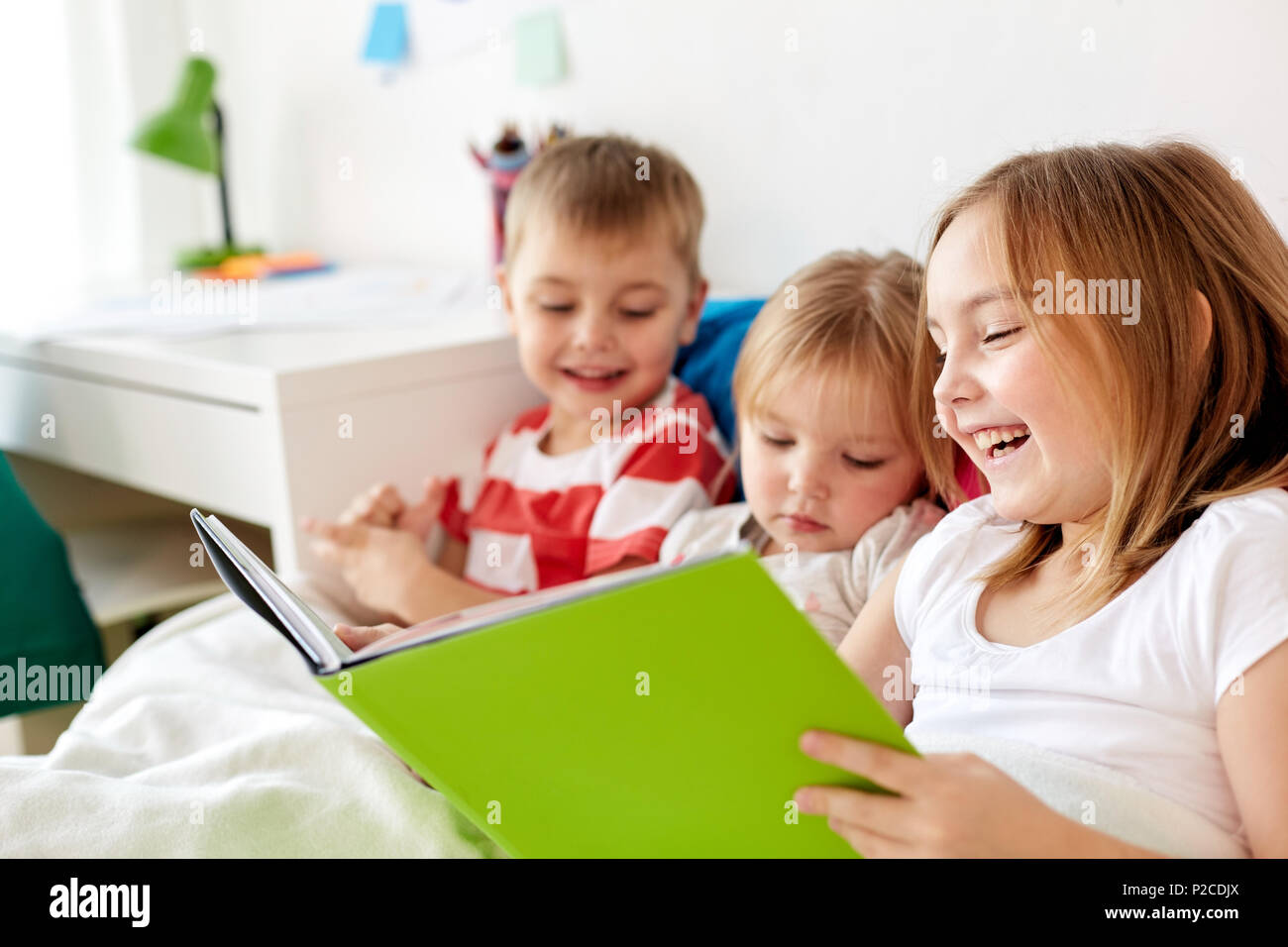 little kids reading book in bed at home Stock Photo - Alamy
