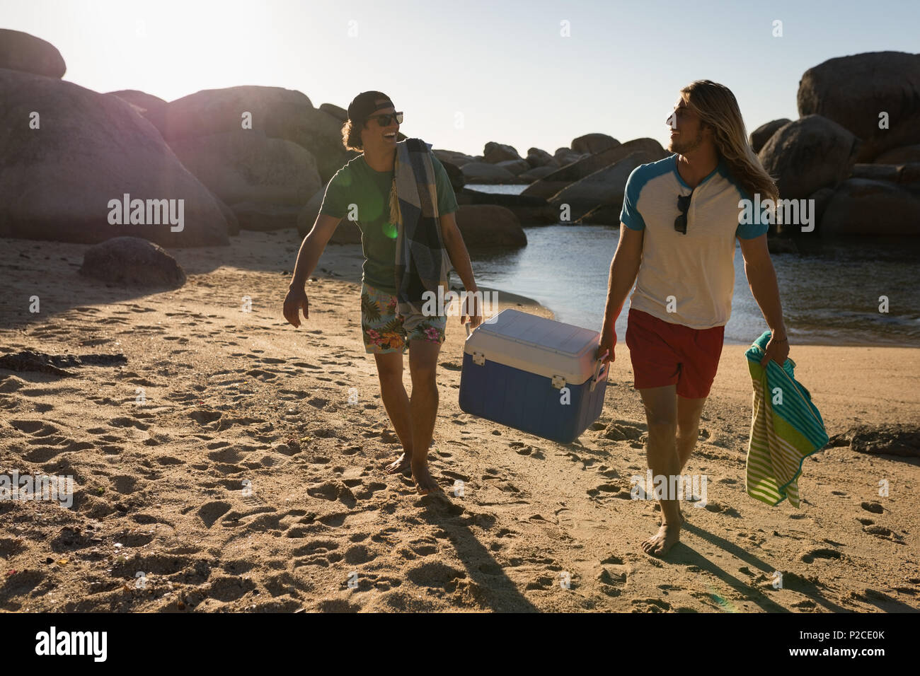 Male friends carrying esky in the beach Stock Photo - Alamy