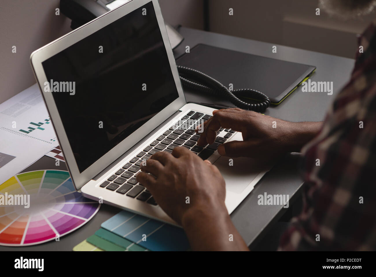 Senior graphic designer using laptop at desk Stock Photo - Alamy