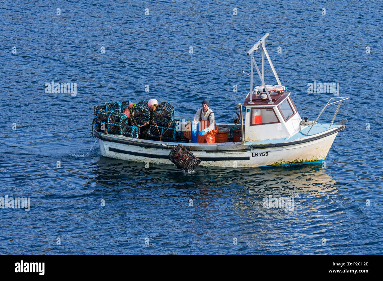 Fisherman in small fishing boat dropping / shooting lobster traps ...