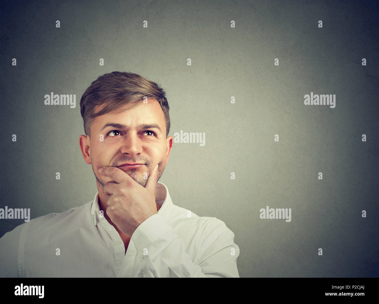 Handsome pensive man holding hand on chin and thinking thoroughly while ...