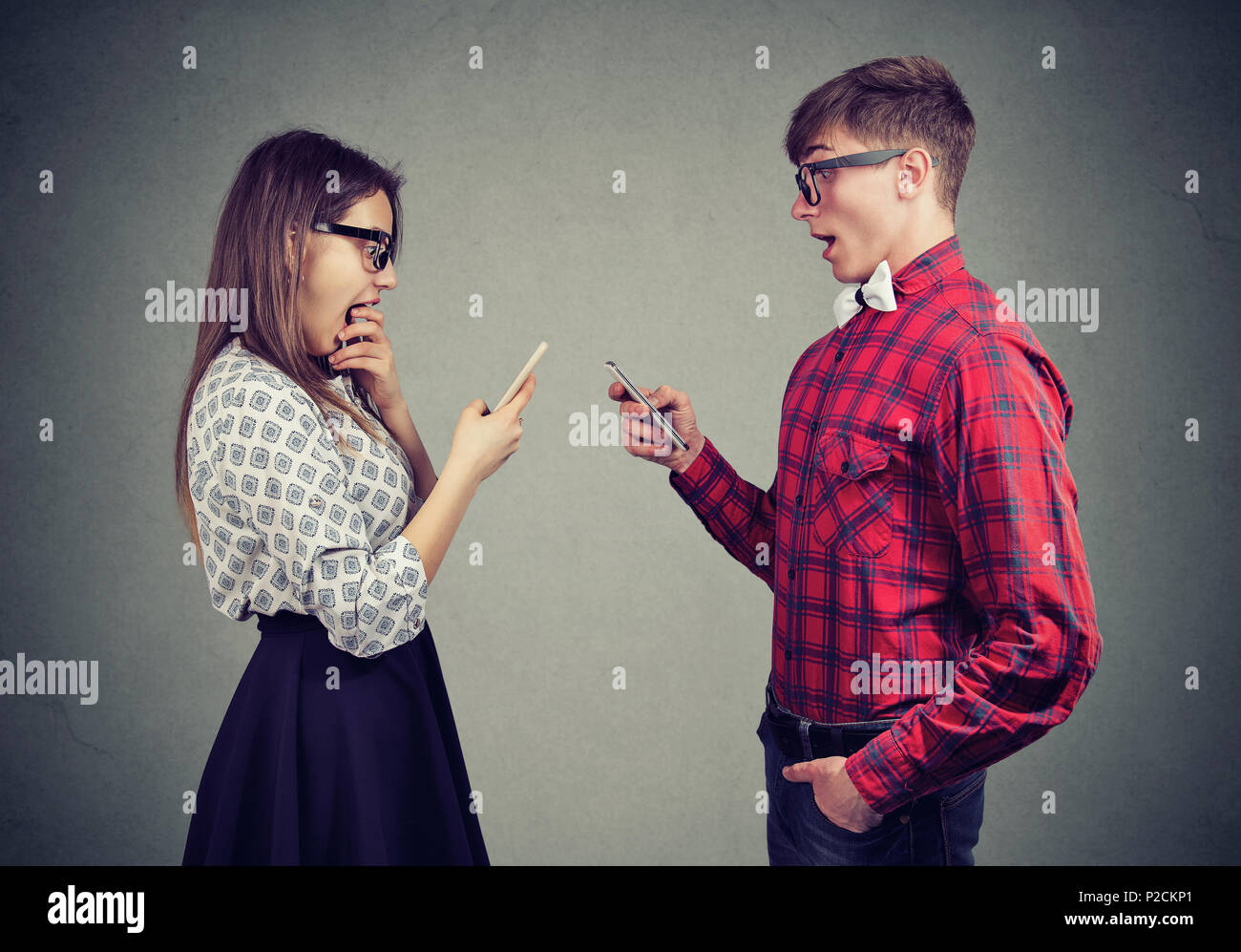 Shocked young couple using smart phones looking stunned Stock Photo - Alamy