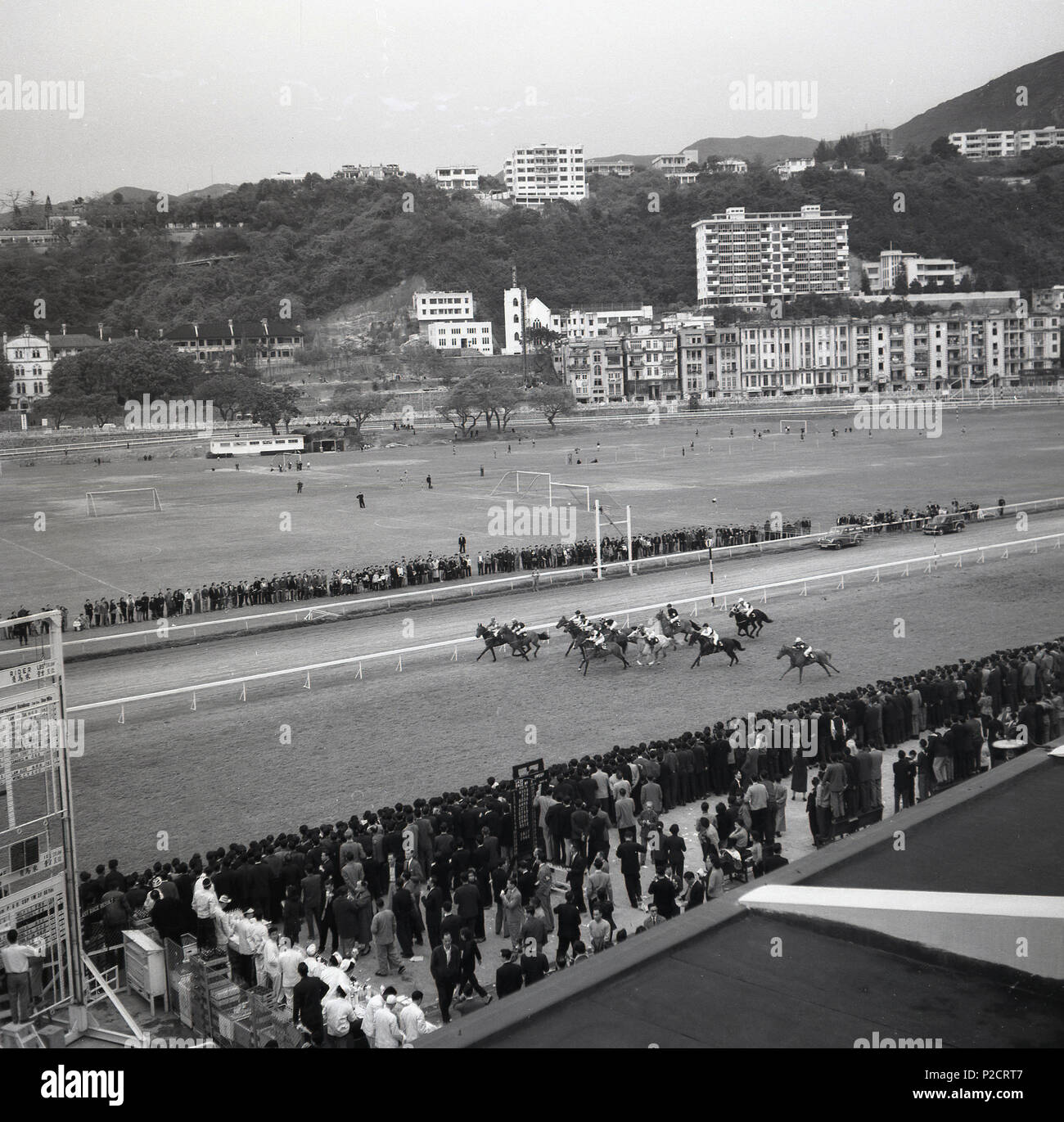 1960s, historlcal, overheard view of spectators watching horse racing ...