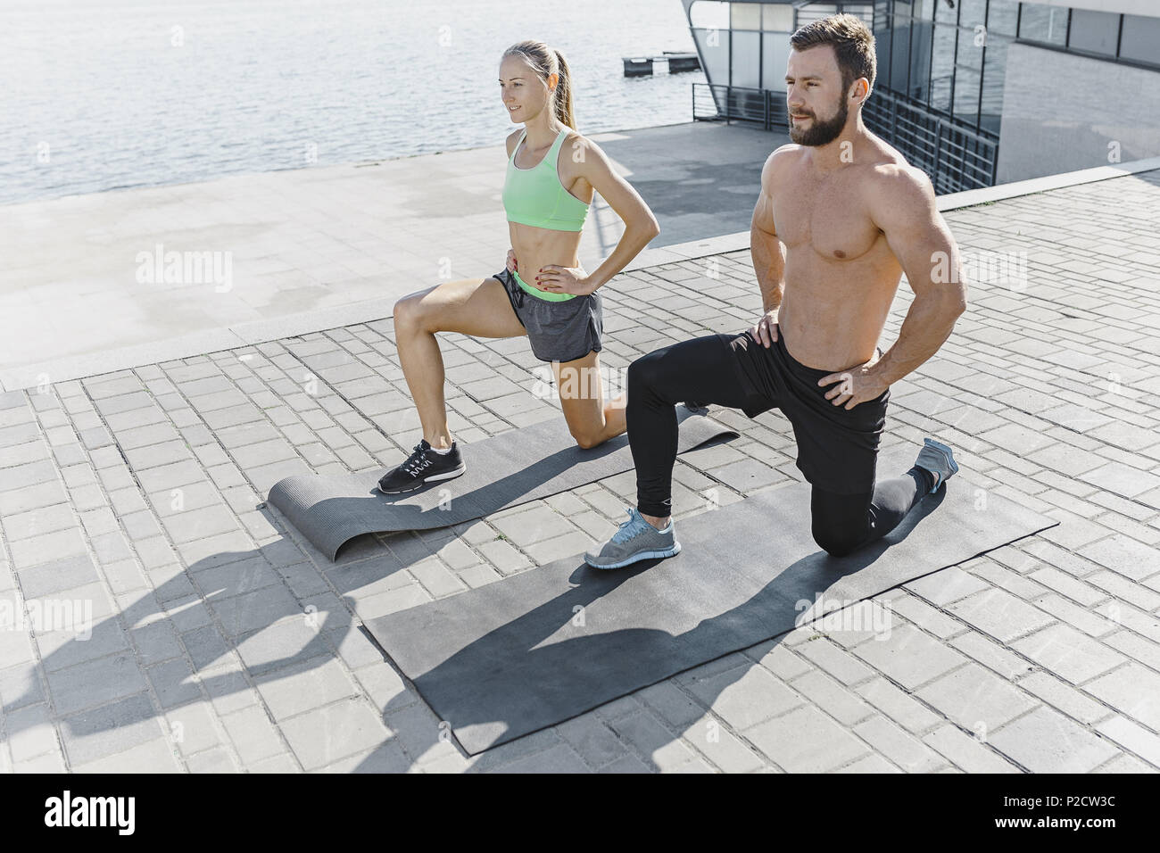 Fit fitness woman and man doing fitness exercises outdoors at city ...