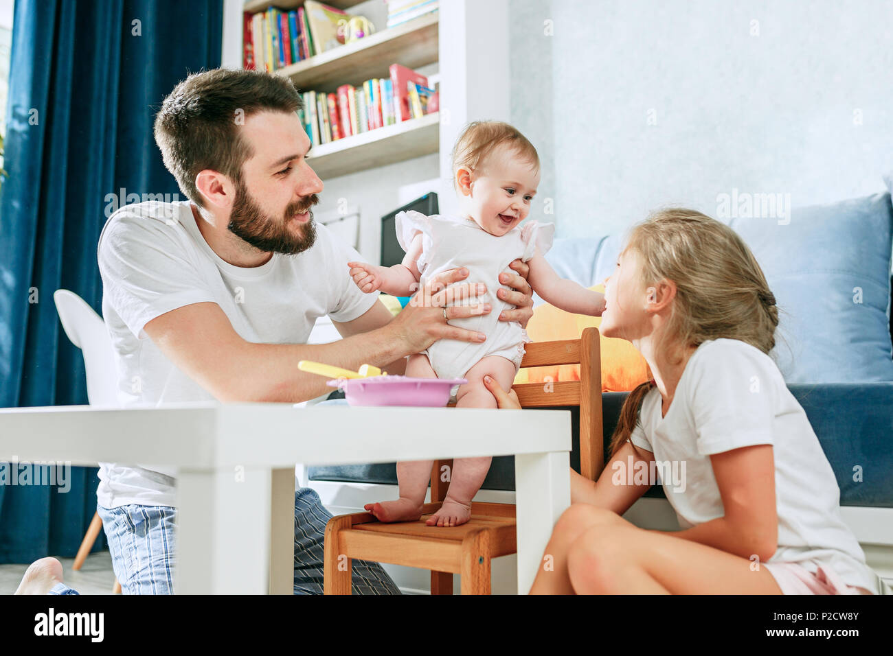 Good looking young man eating breakfast and feeding her baby girl at ...