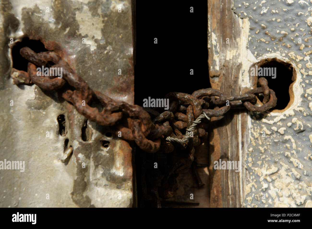 Close-up, detail, old rusting chain, wire holding dilapidated door ...