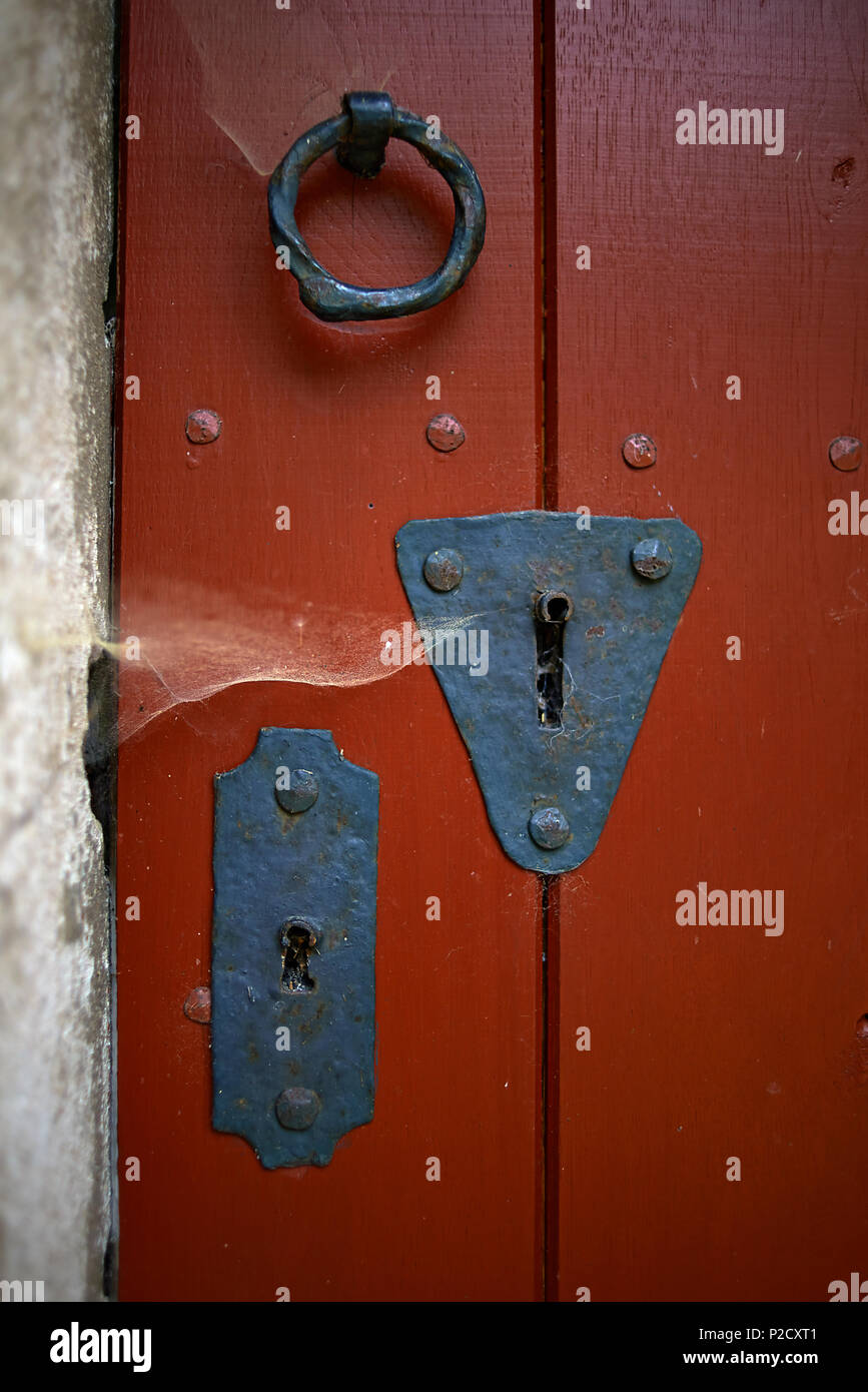 Close up of a wooden red door with big black metal key holes in an arch ...