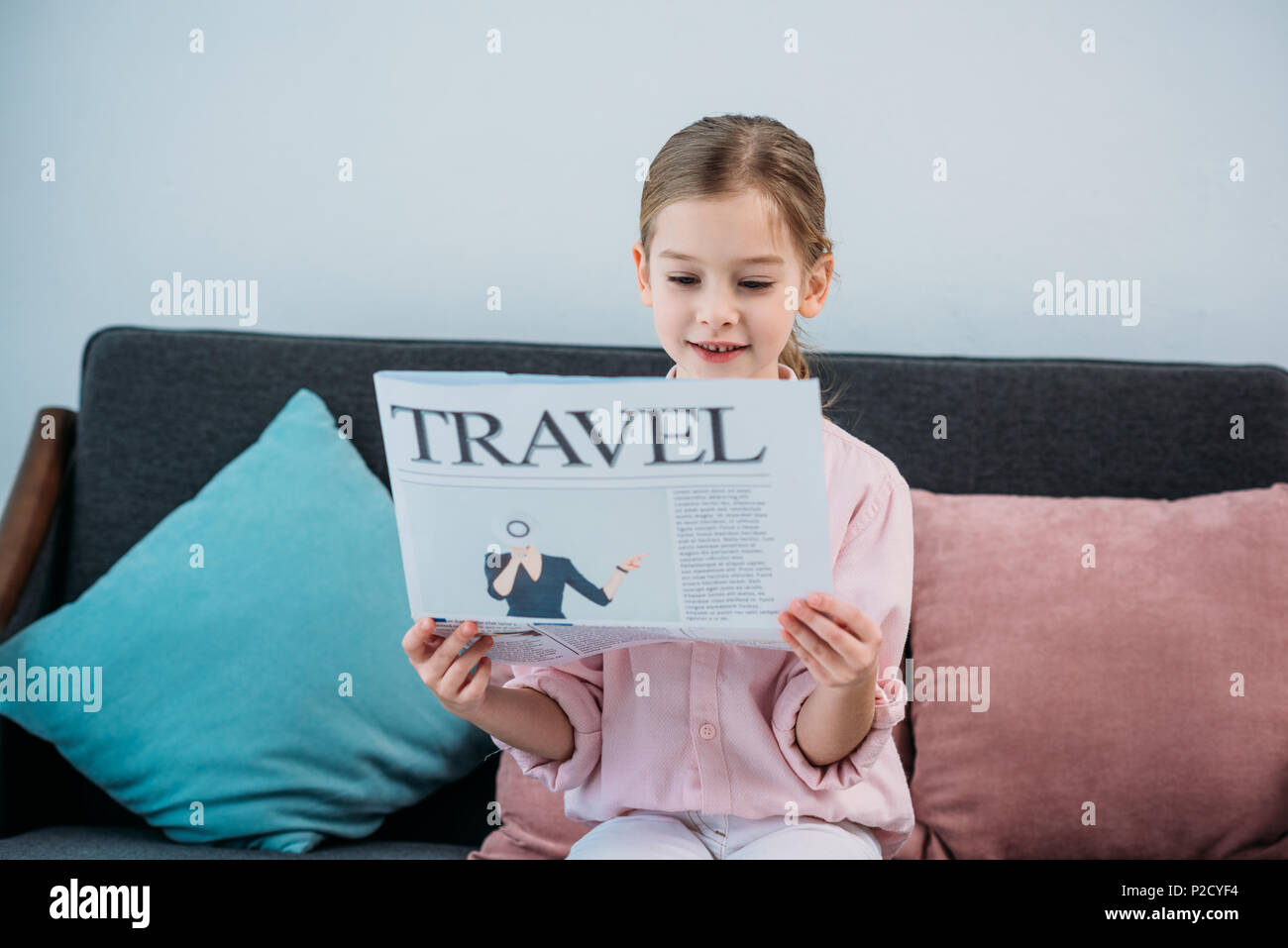portrait of cute child reading travel newspaper while resting on sofa ...
