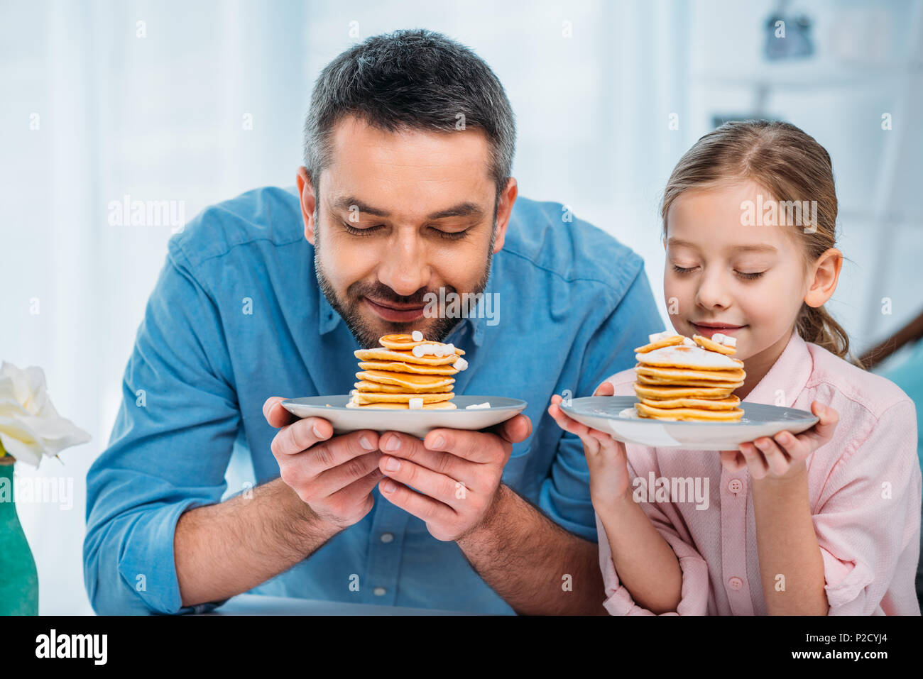 portrait of father and little daughter sniffing pancakes for breakfast ...
