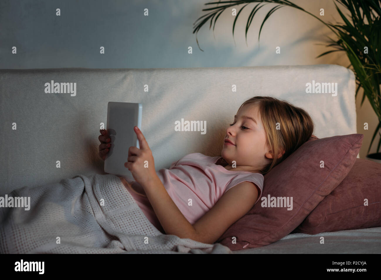 side view of little kid using tablet in bed at home Stock Photo - Alamy
