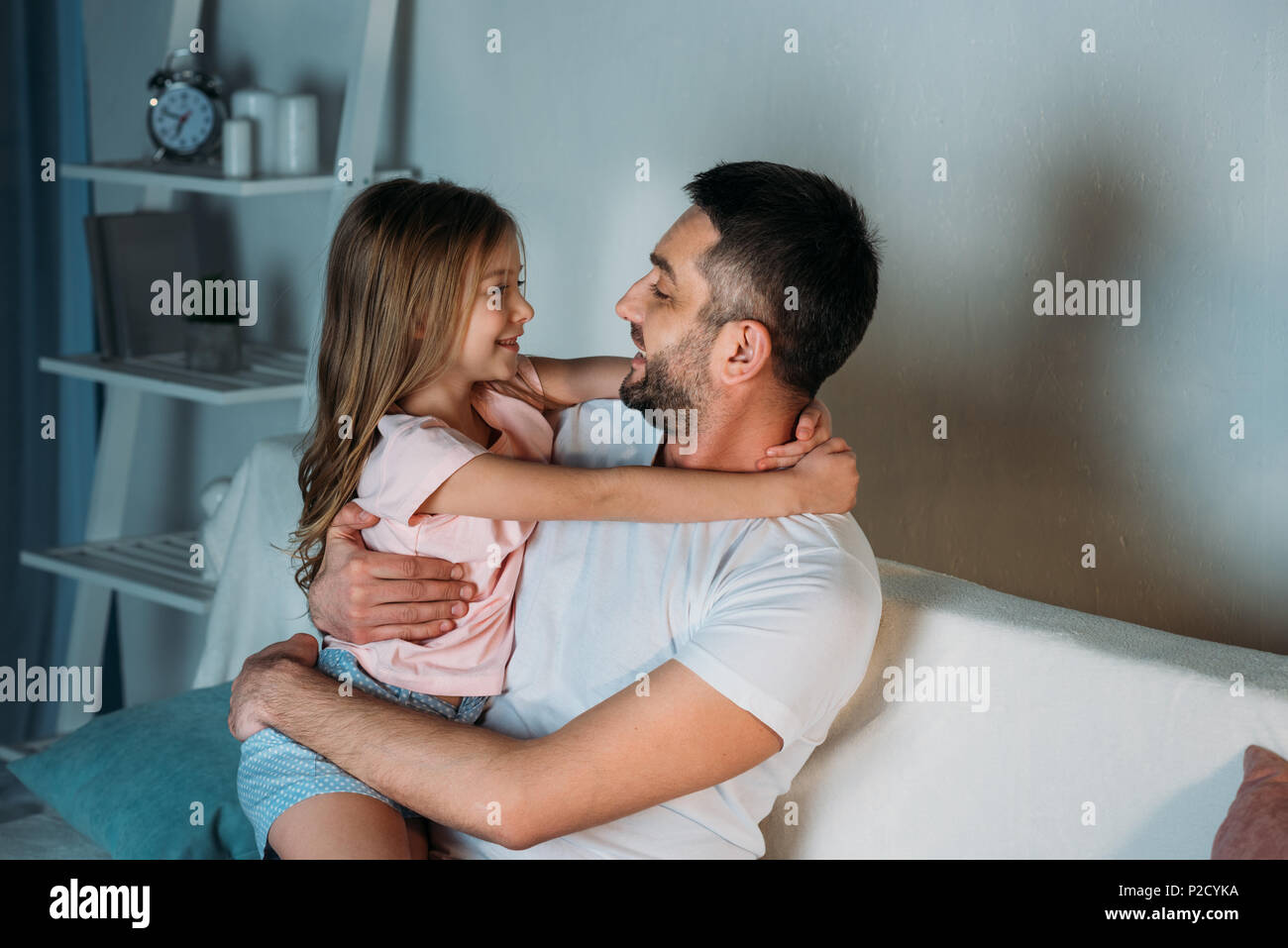 side view of smiling father and daughter looking at each other at home ...