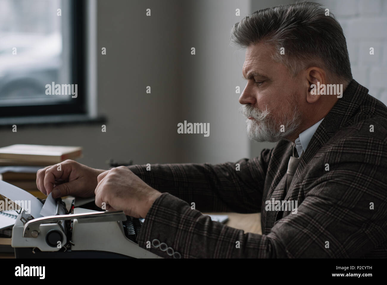 handsome senior writer loading paper into typewriter Stock Photo - Alamy