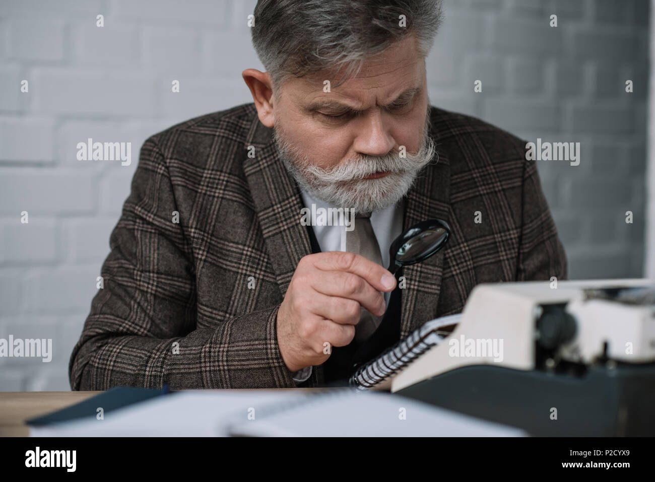 bearded senior writer reading manuscript with magnifying glass Stock ...