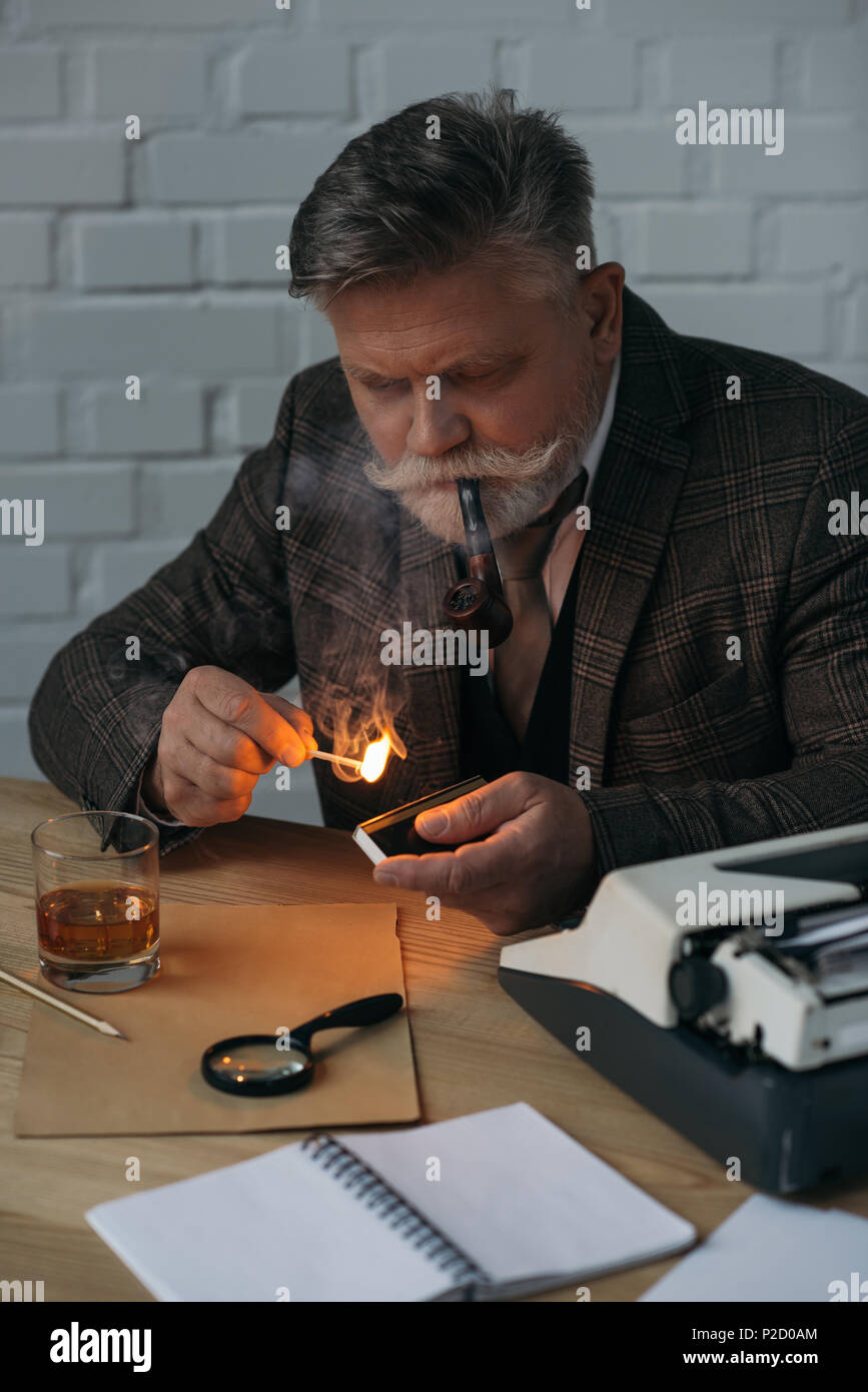 senior writer with burning match smoking pipe at workplace Stock Photo ...