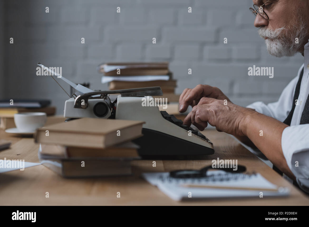 side view of serious senior writer working with typewriter Stock Photo ...