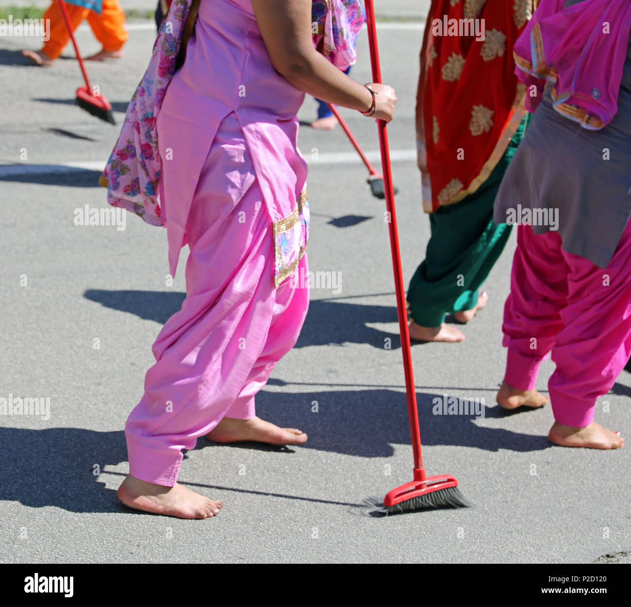 Sikh woman walking barefoot cleans the street with a broom during a ...
